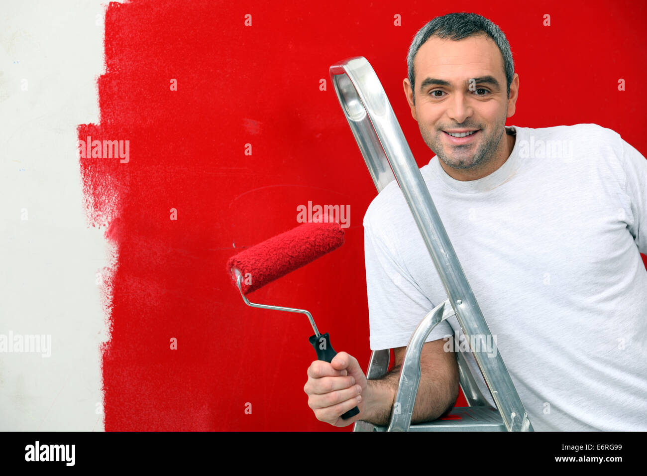 A man painting a wall red Stock Photo - Alamy
