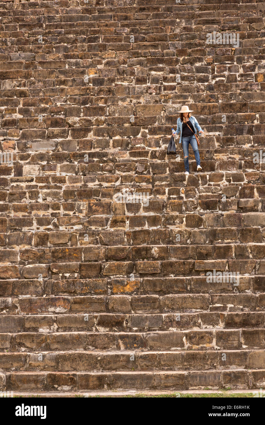 A tourists walks down the steps of the south platform of Monte Albán ...