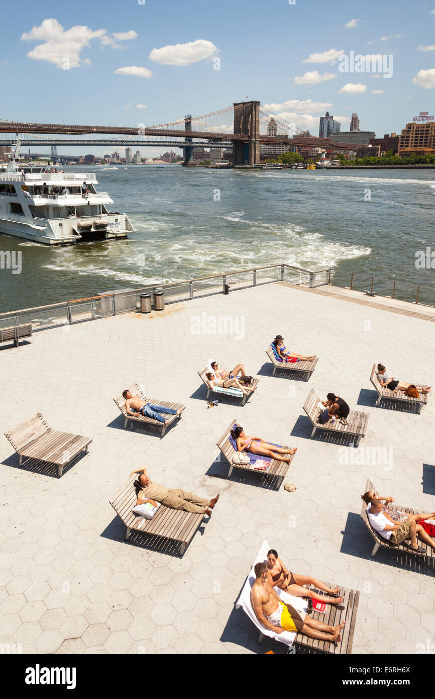 People sunbathing beside East River, Brooklyn Bridge and South Street ...
