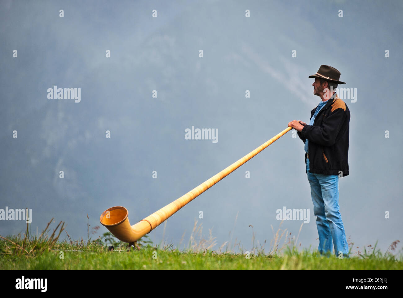A solitary man, preparing to play his alphorn on a ridge above the ...