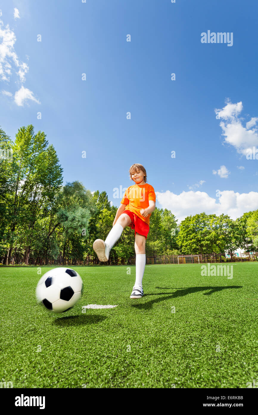 Boy kicking football with one leg Stock Photo - Alamy