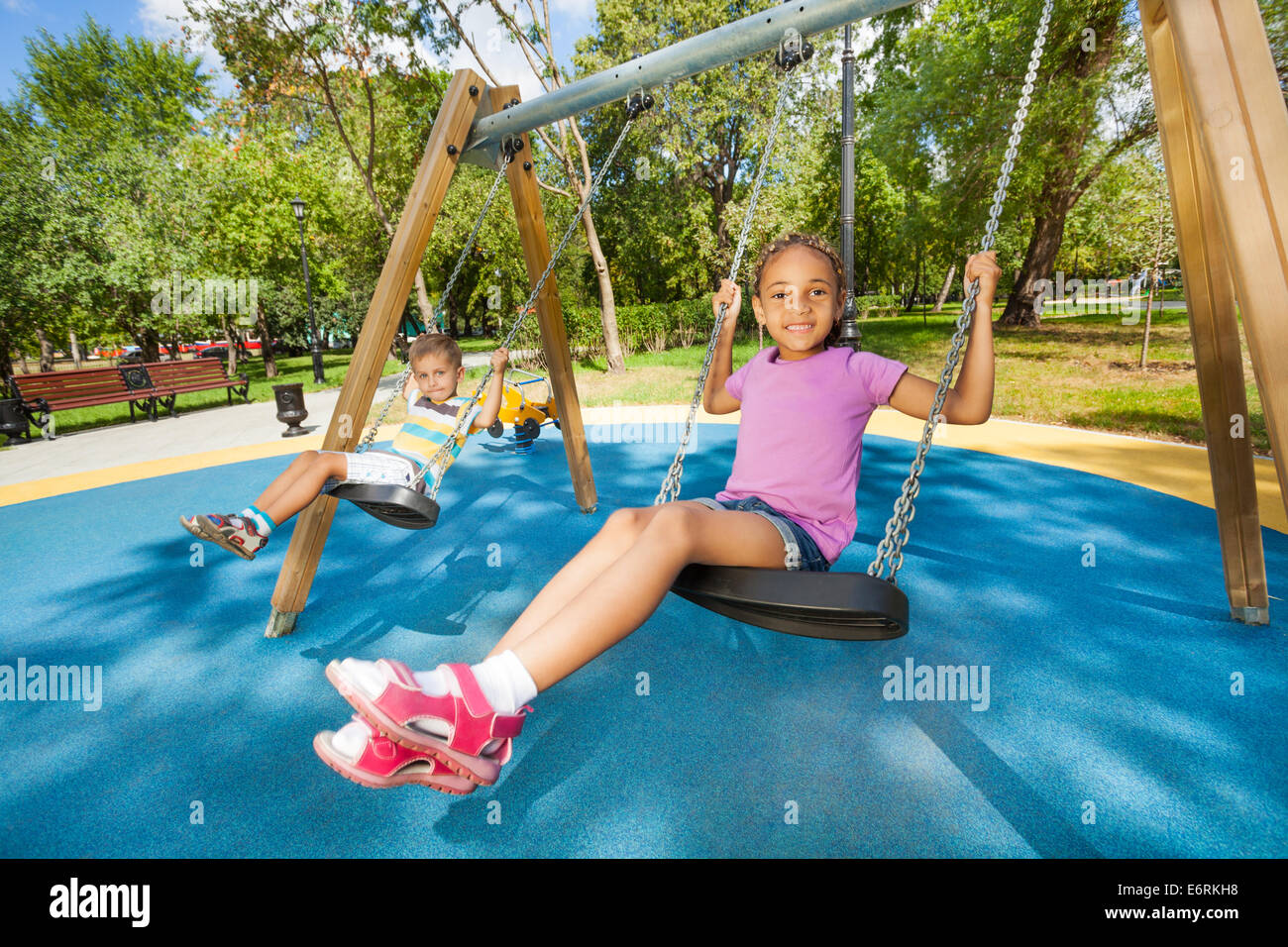 Kids swinging on playground Stock Photo - Alamy
