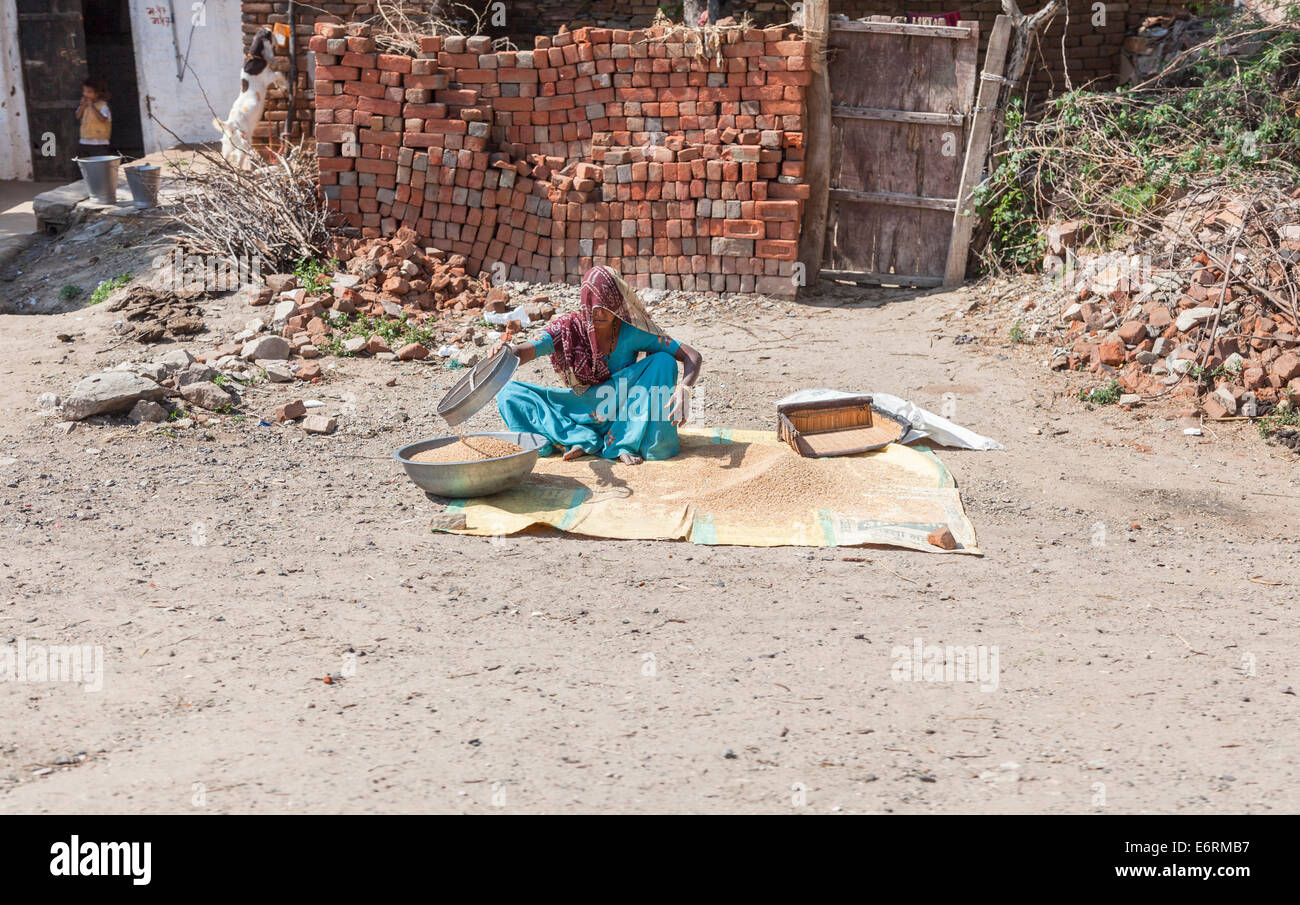 Local woman sitting on the roadside, working sifting grain, in a ...