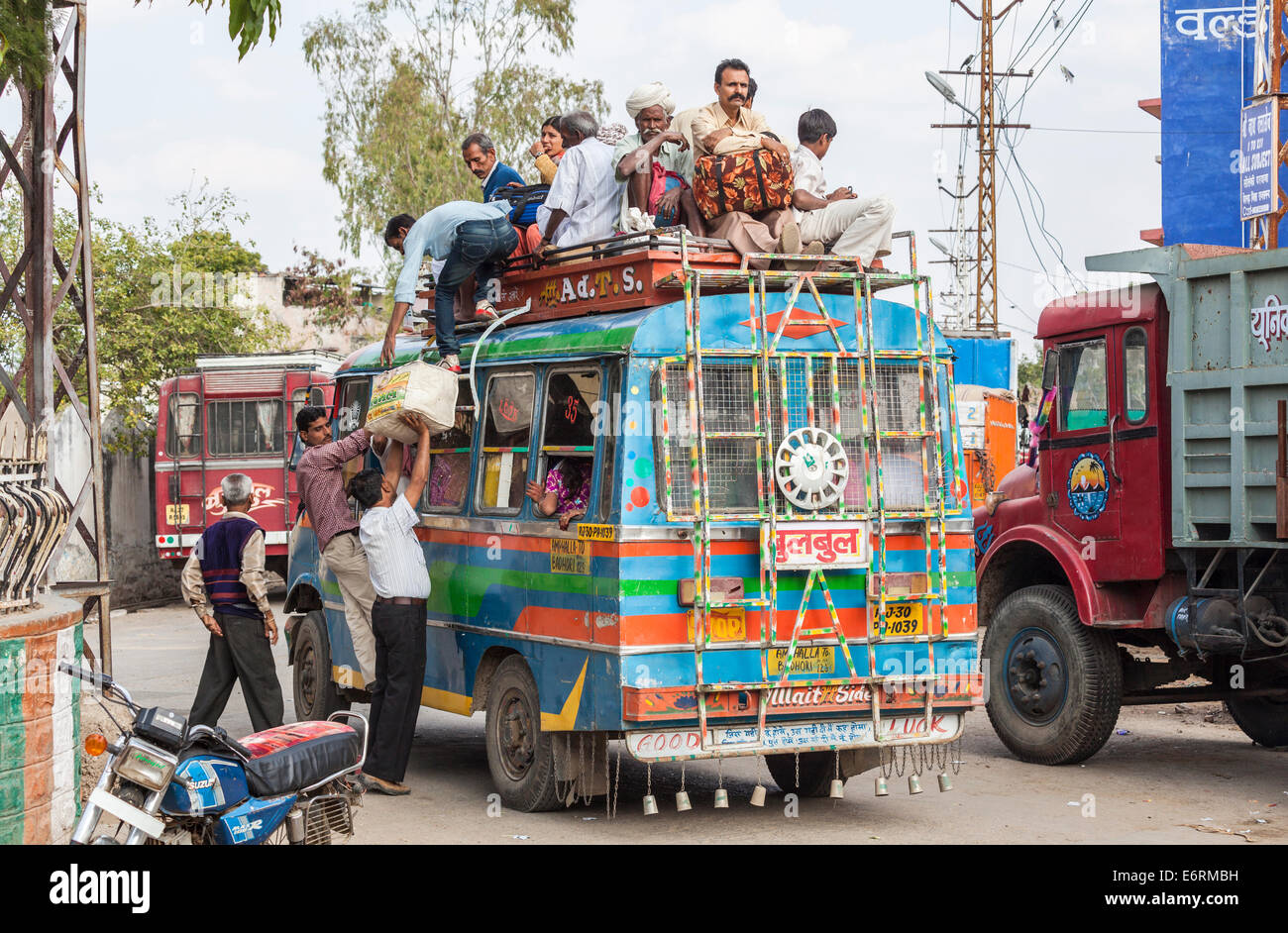 Local people load and crowd into a colourful bus and sit on the roof in ...