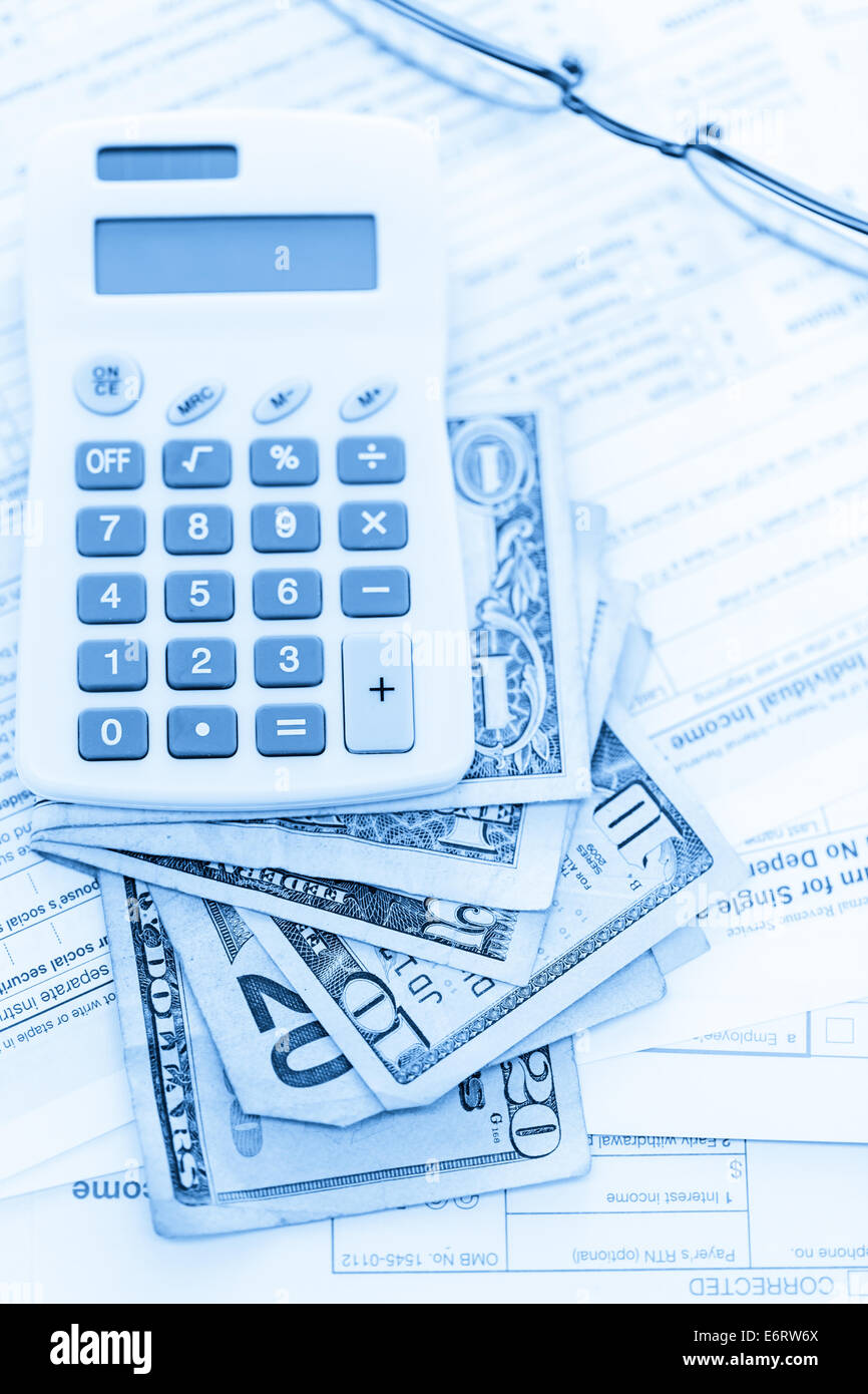 Calculating income tax return with folded cash on a table Stock Photo ...