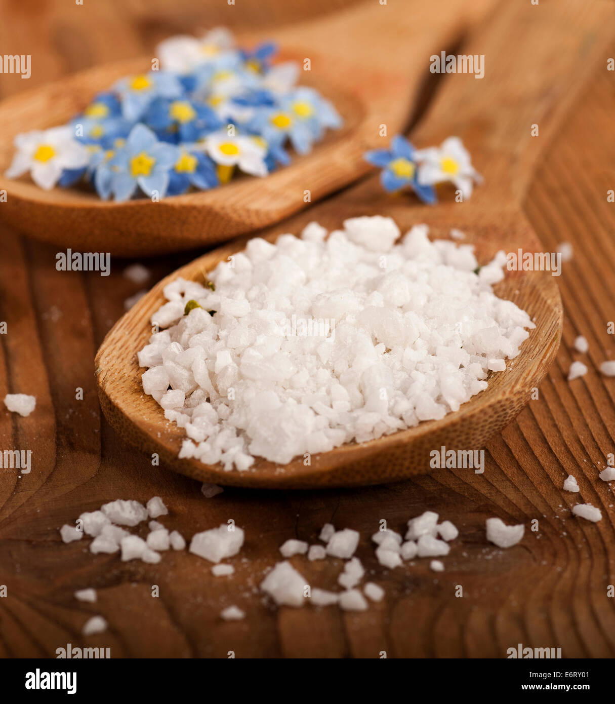 Spa background with sea salt and flowers in wooden spoons on wooden ...