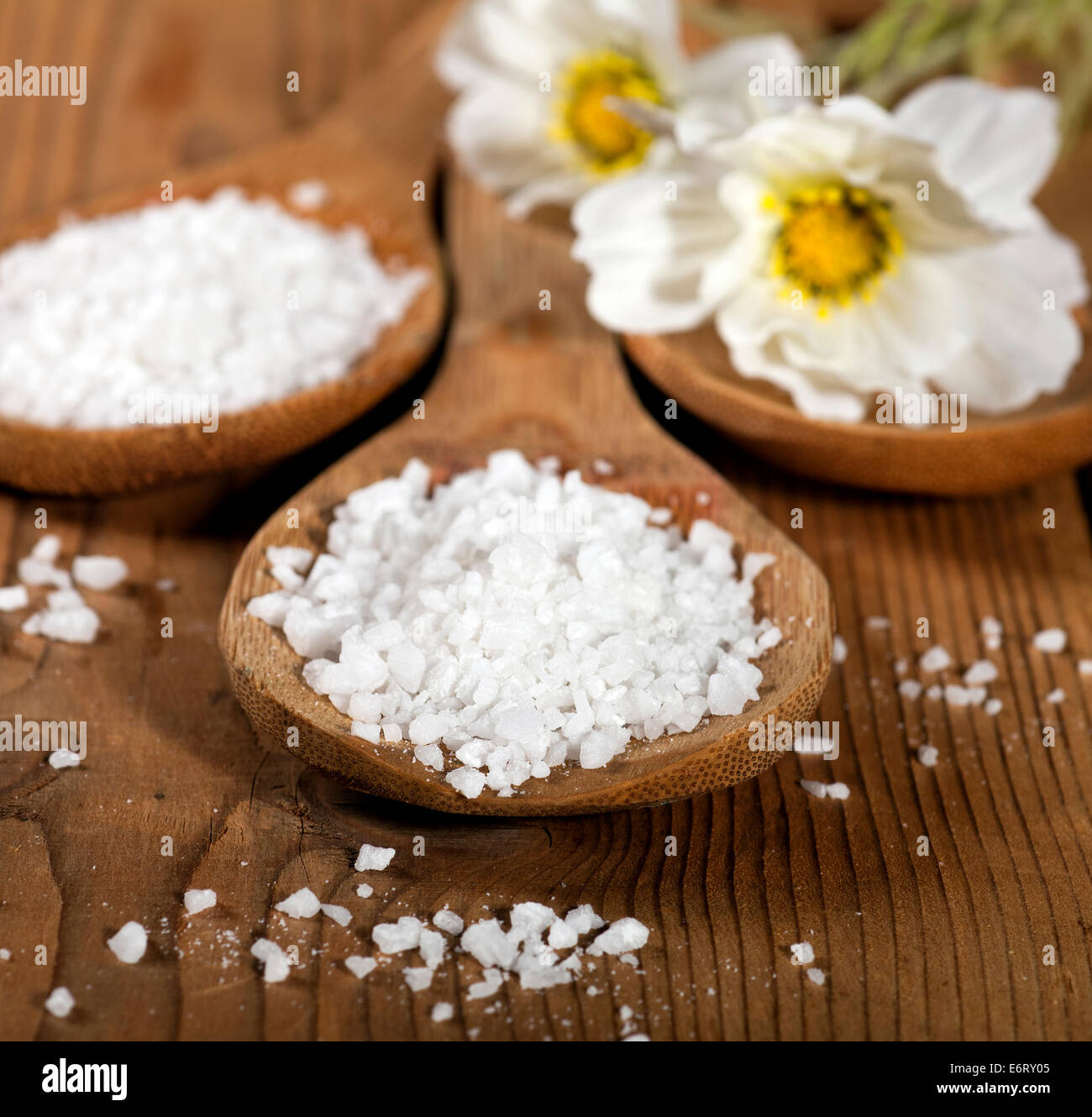 Spa background with sea salt and flowers in wooden spoons on wooden ...