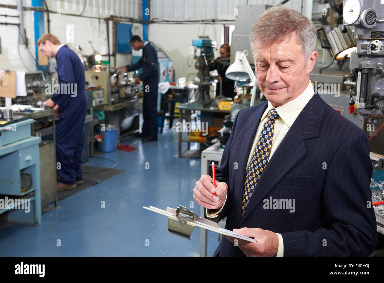 Owner Of Engineering Factory With Staff In Background Stock Photo - Alamy