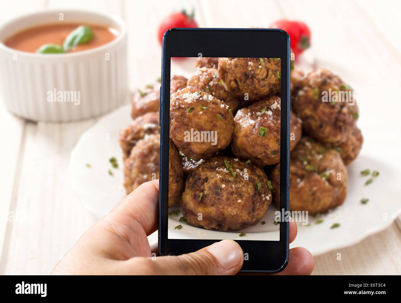 Man shooting with his cell phone camera meat balls.Selective focus on ...