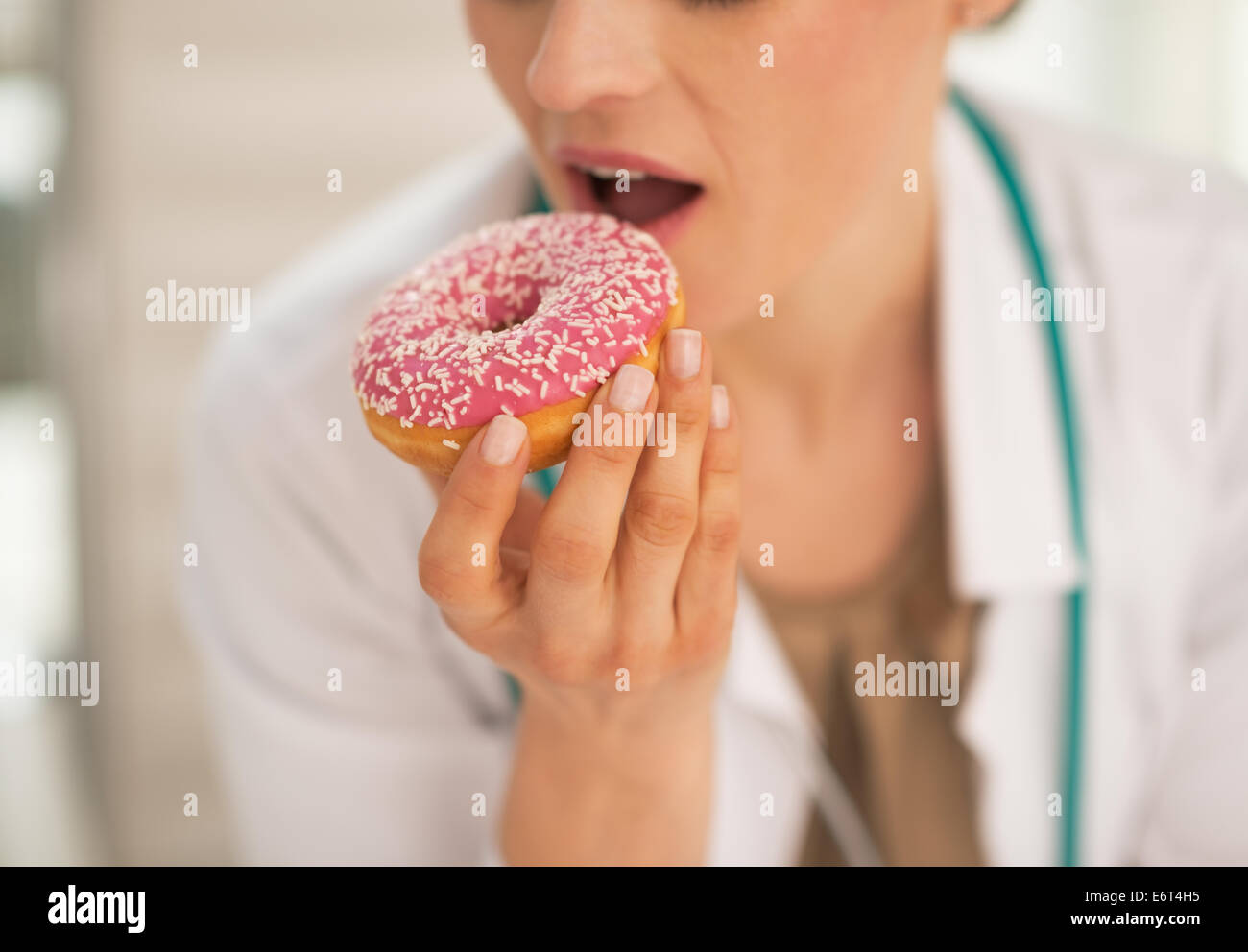 Closeup on doctor woman biting donut Stock Photo - Alamy