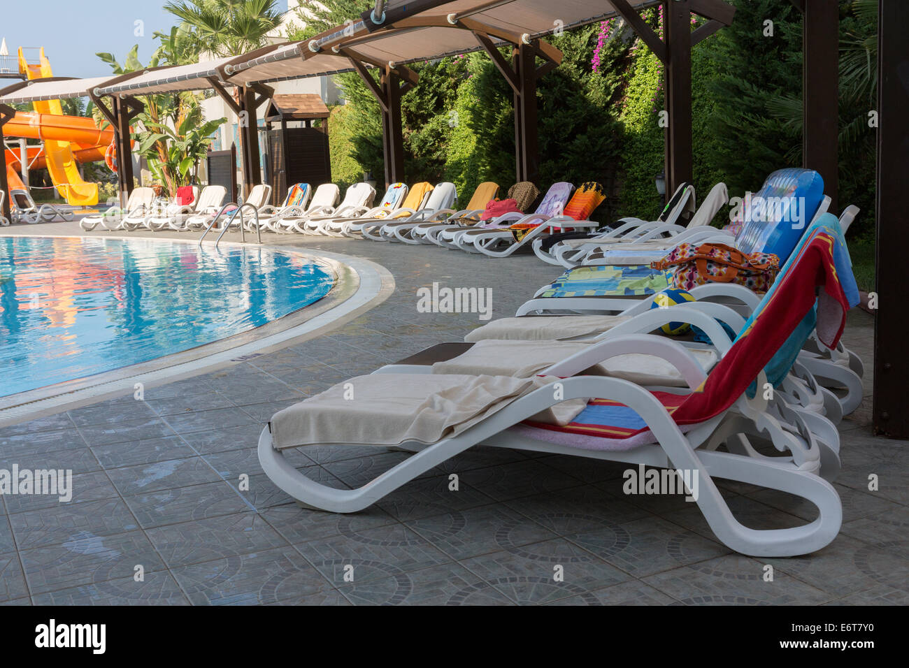 Loungers around a holiday hotel pool are reserved by people placing ...