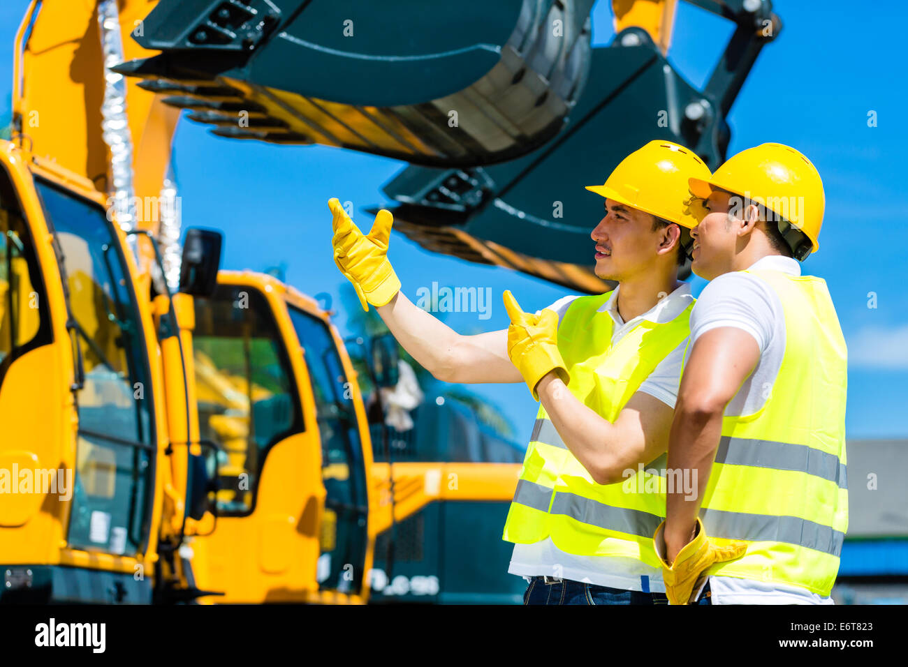Asian worker at construction machinery of construction site or mining ...