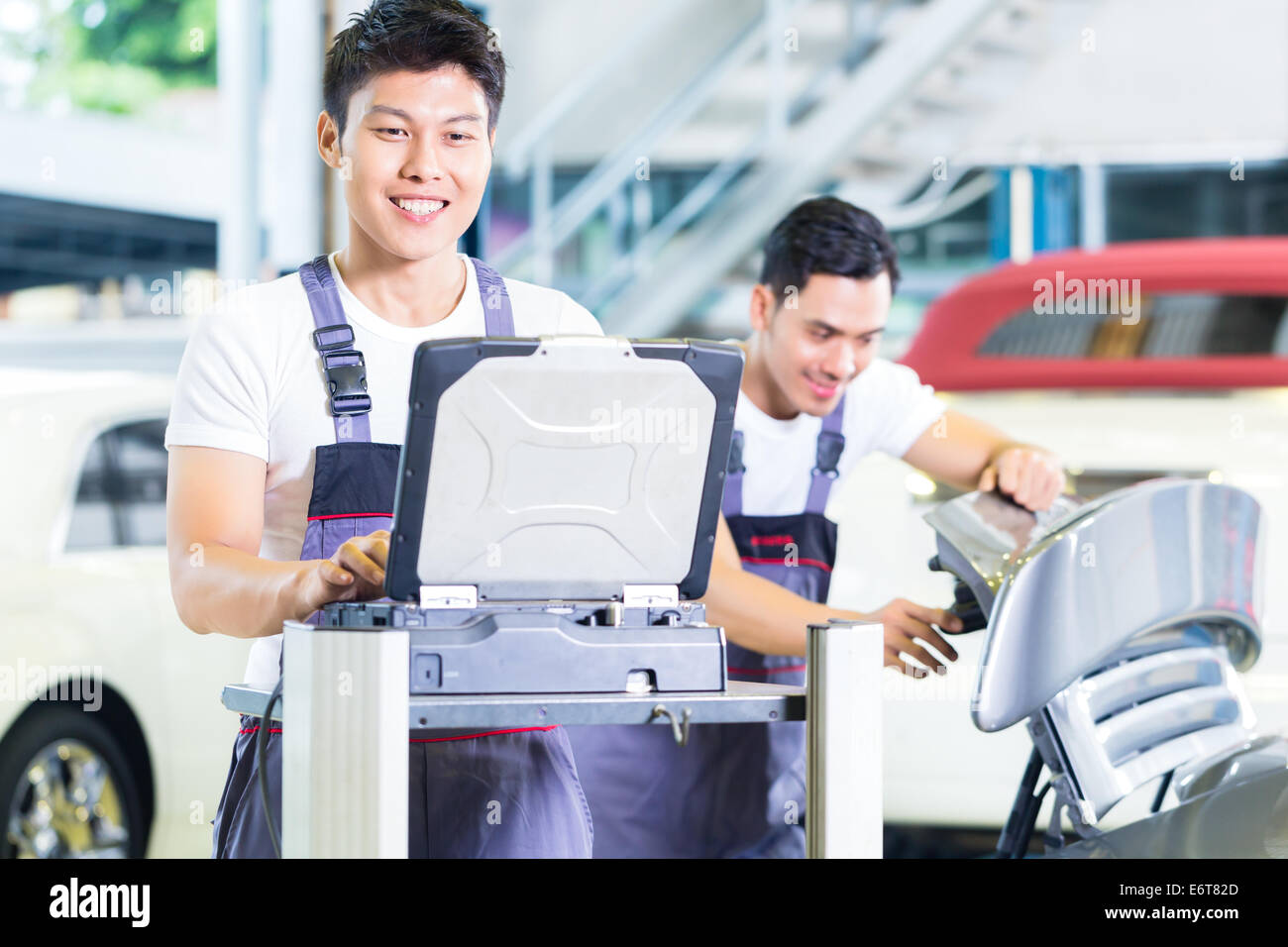 Asian Chinese car mechanics checking auto engine with diagnostics tool ...