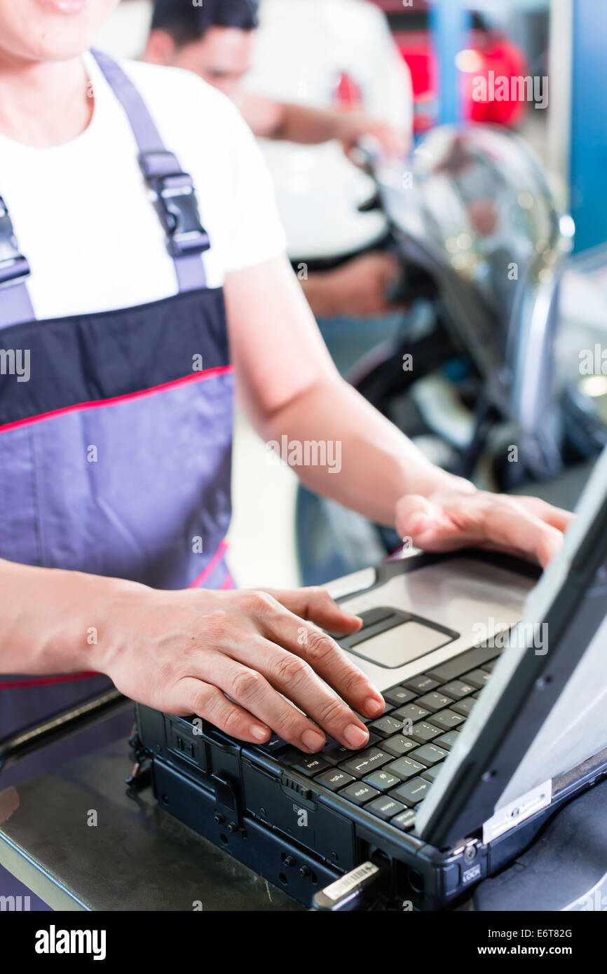 car mechanic checking auto engine with diagnostics tool in his workshop ...
