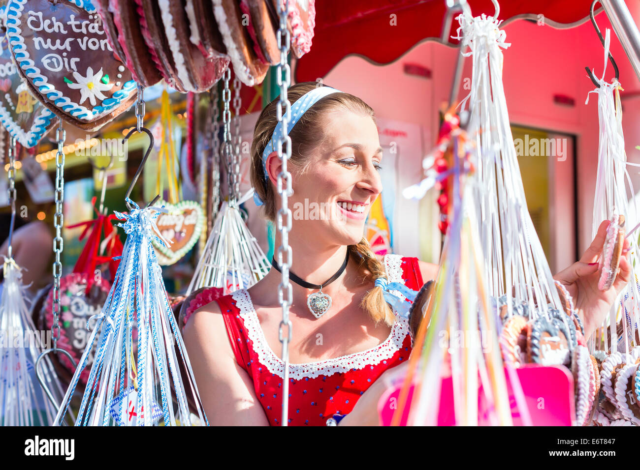 Woman selecting gingerbread heart at Oktoberfest wearing Dirndl Stock ...