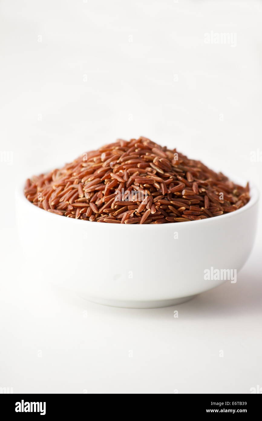 Red rice in a white bowl on white background Stock Photo - Alamy