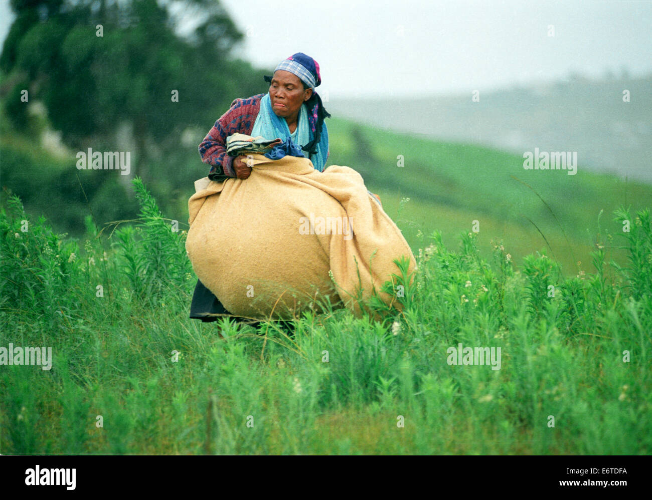 A panicked woman holds her belongings in a rolled up blanket as she ...