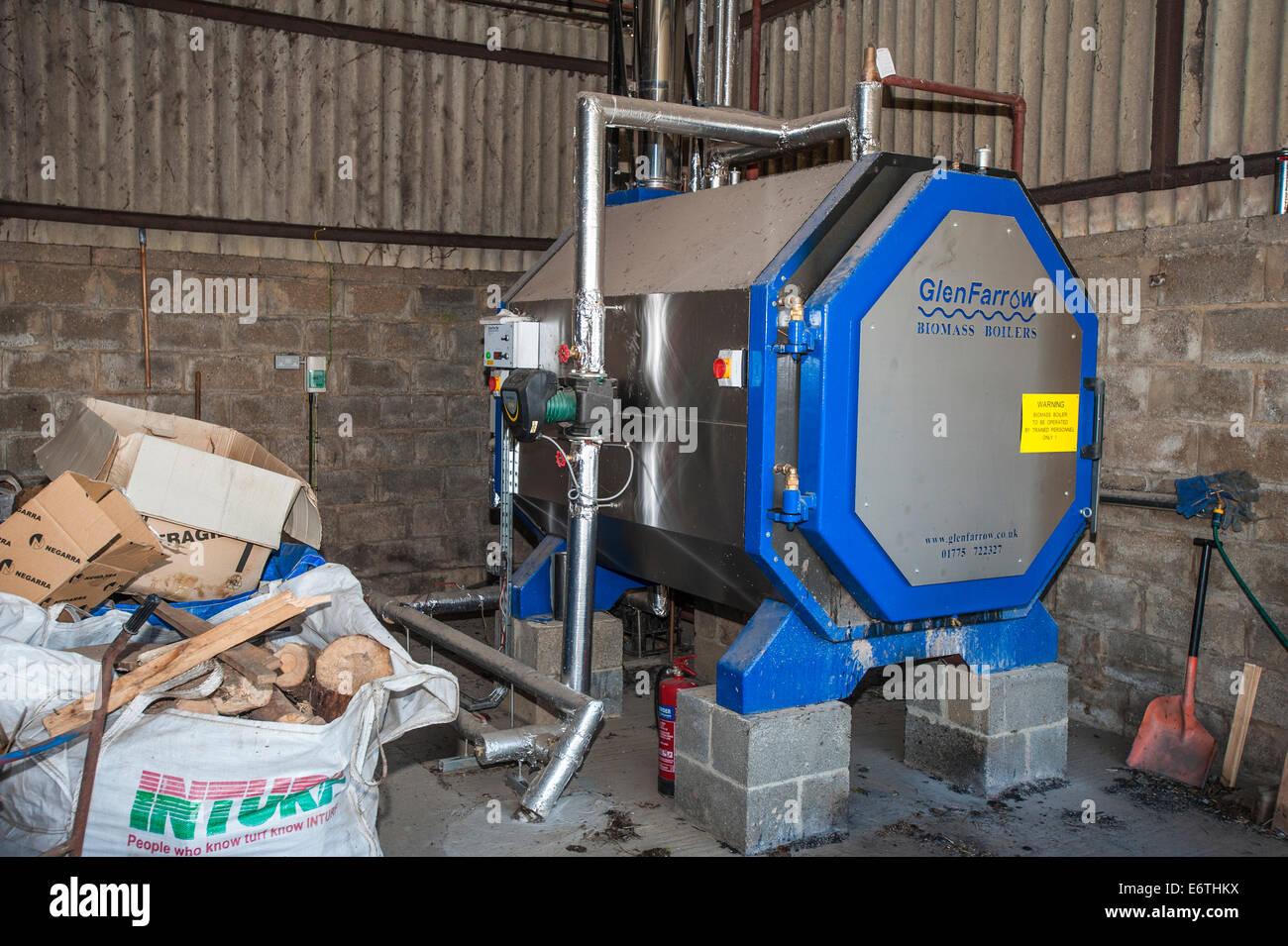 A biomass boiler in a Lincolnshire farmer's barn with a pile of logs ...