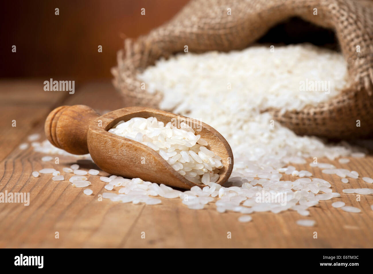 White rice in a sack and wooden scoops on wooden background Stock Photo ...