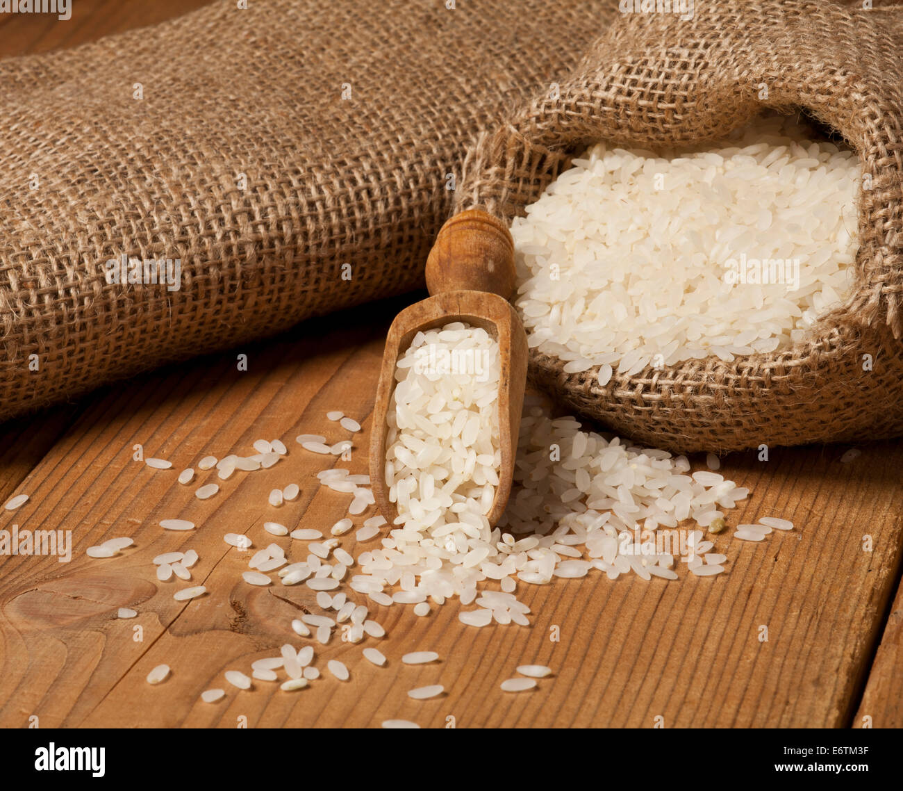 White rice in a sack and wooden scoops on wooden background Stock Photo ...