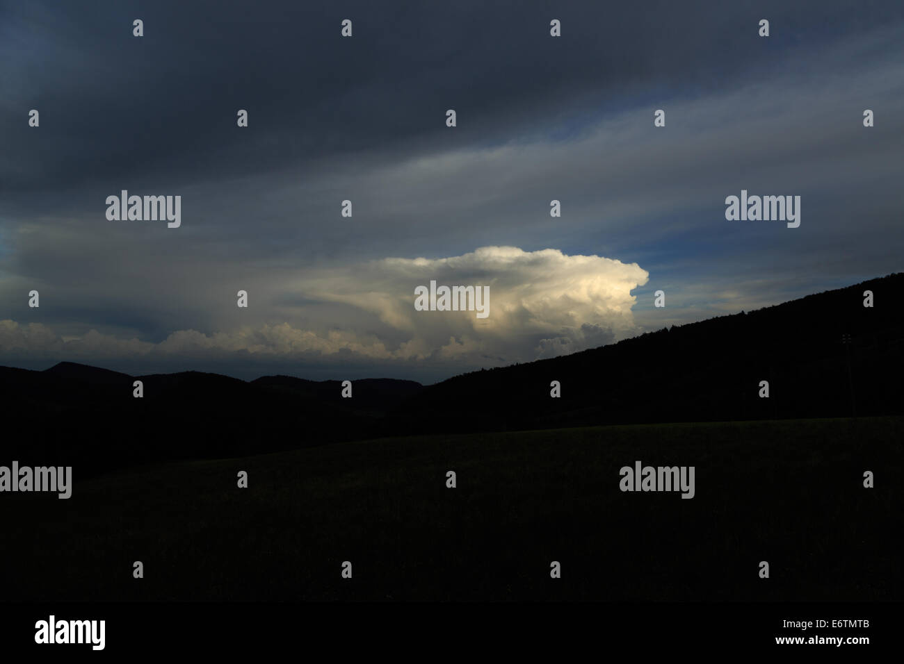 A photograph of some cumulus storm clouds building over a darkened ...