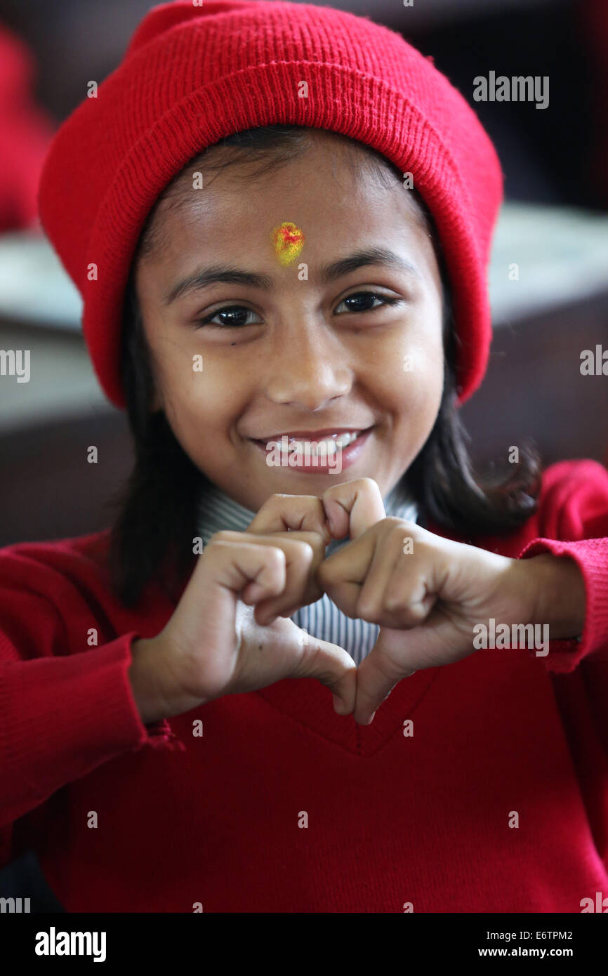Portrait of a nepalese girl in school uniform making a heart shape with ...