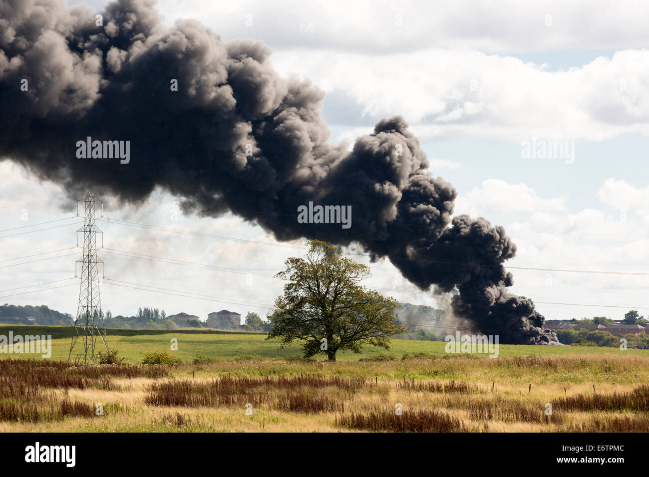 A rural fire in a field producing a large plume of thick black smoke ...