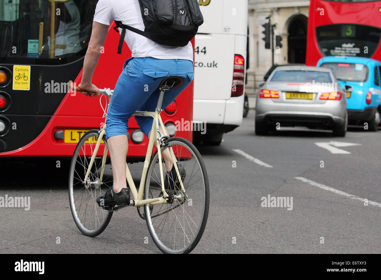 A cycling riding behind a bus and other traffic in London Stock Photo ...
