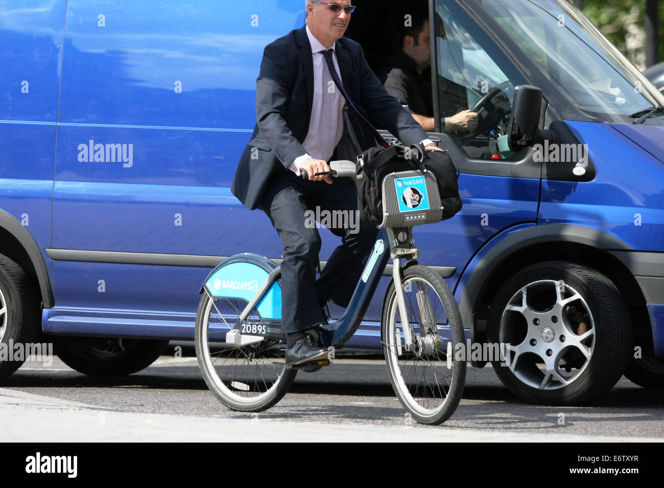 A cyclist riding alongside a blue van in London Stock Photo - Alamy