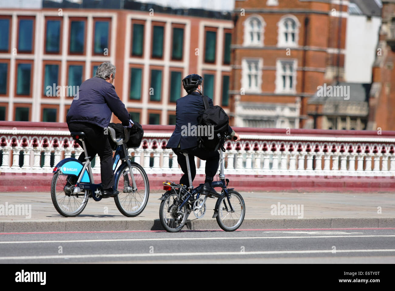 Two cyclists riding over Waterloo Bridge, one on the pavement, one on ...