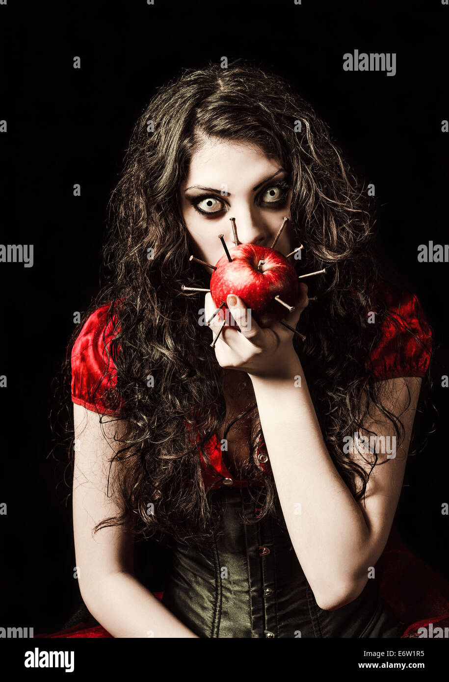 Horror shot: the strange scary girl eats apple studded with nails Stock ...