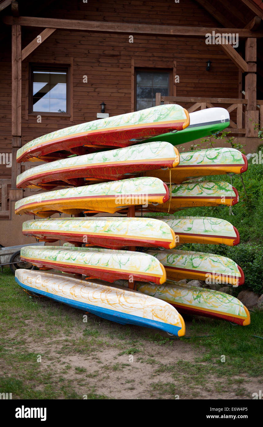 Dozen kayaks drying on stand in marina Stock Photo - Alamy