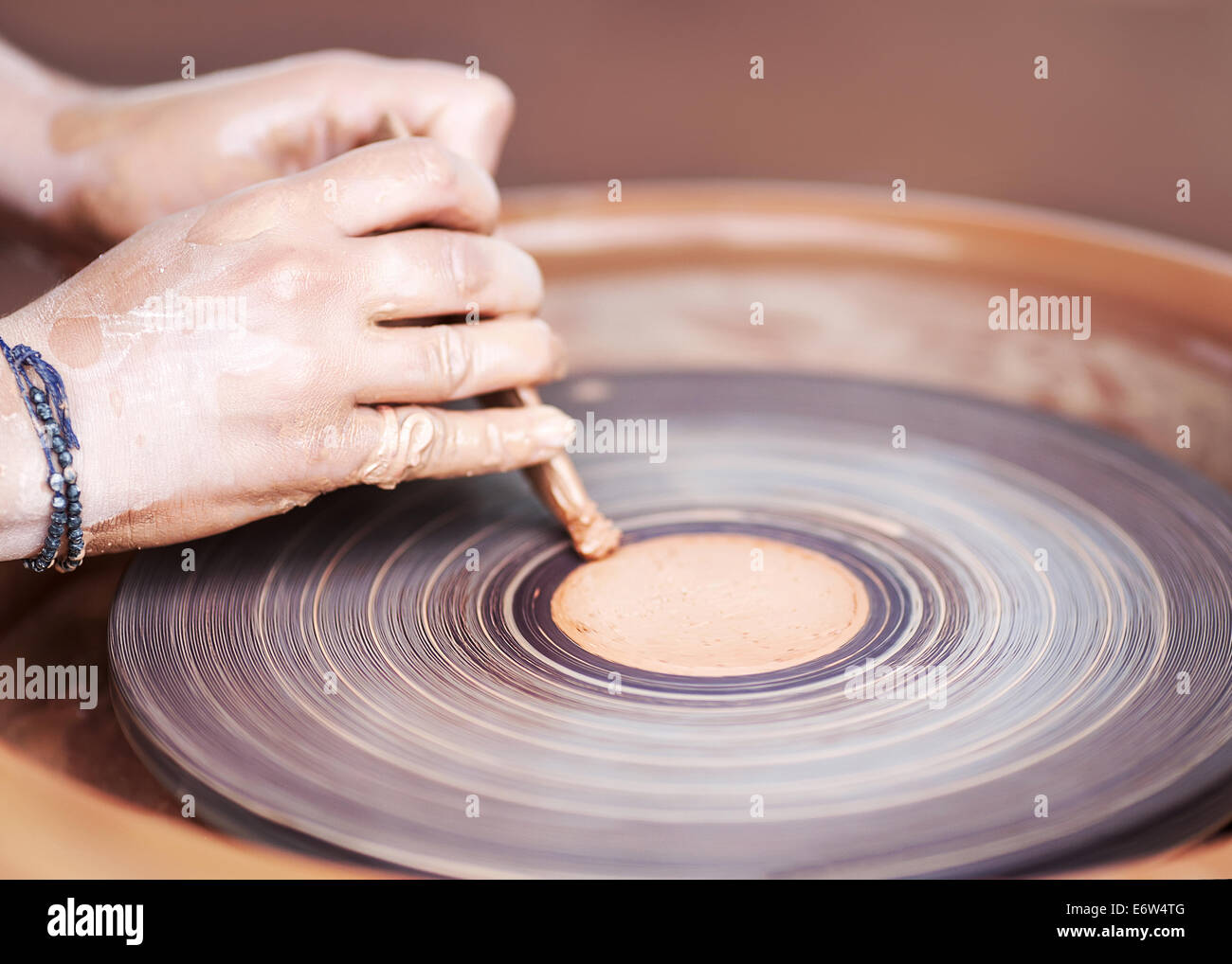 Hands working on pottery wheel , close up retro style toned photo wit ...