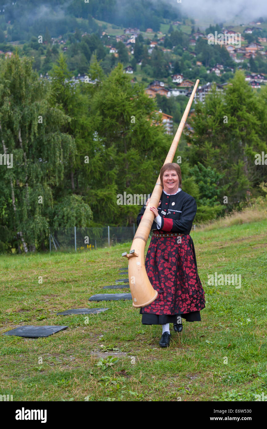 A Swiss woman alphorn player smiles as she carries her instrument ...