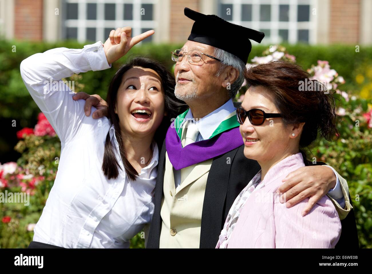 young asian female student at graduation ceremony with her parents ...