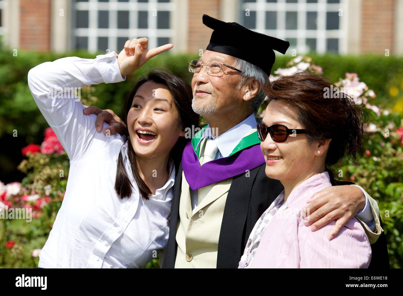 young asian female student at graduation ceremony with her parents ...