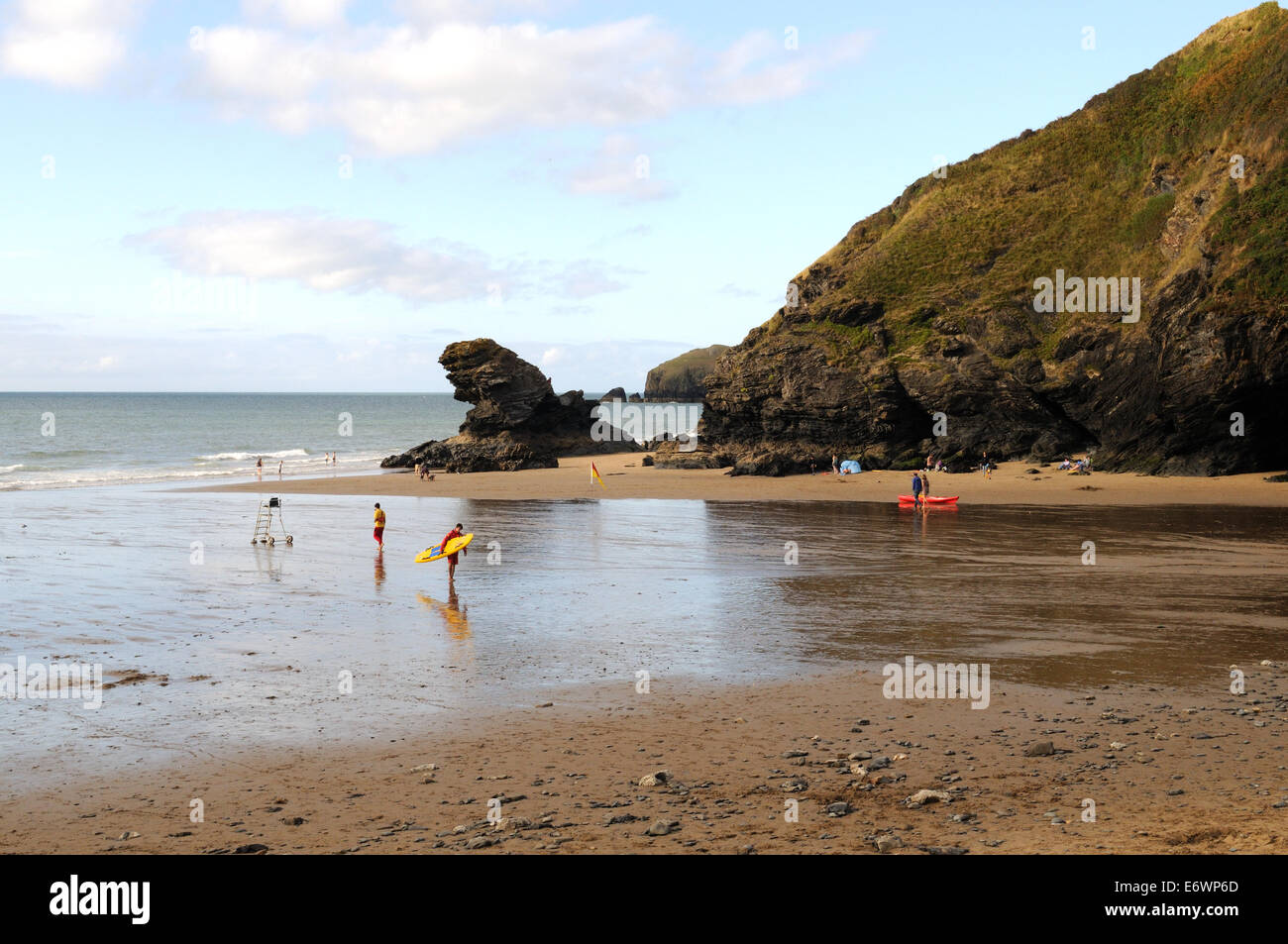 Lifeguards carrying kayak on Llangrannog Beach Ceredigion Wales Cymru ...