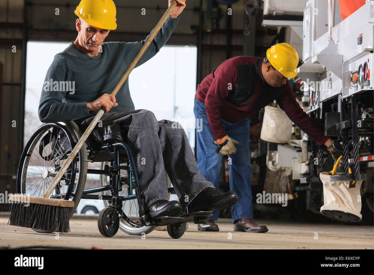 Maintenance technicians cleaning in utility truck garage at electric ...