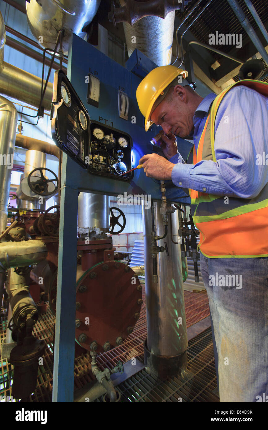 Engineer in electric power plant reviewing sensor readings with ...