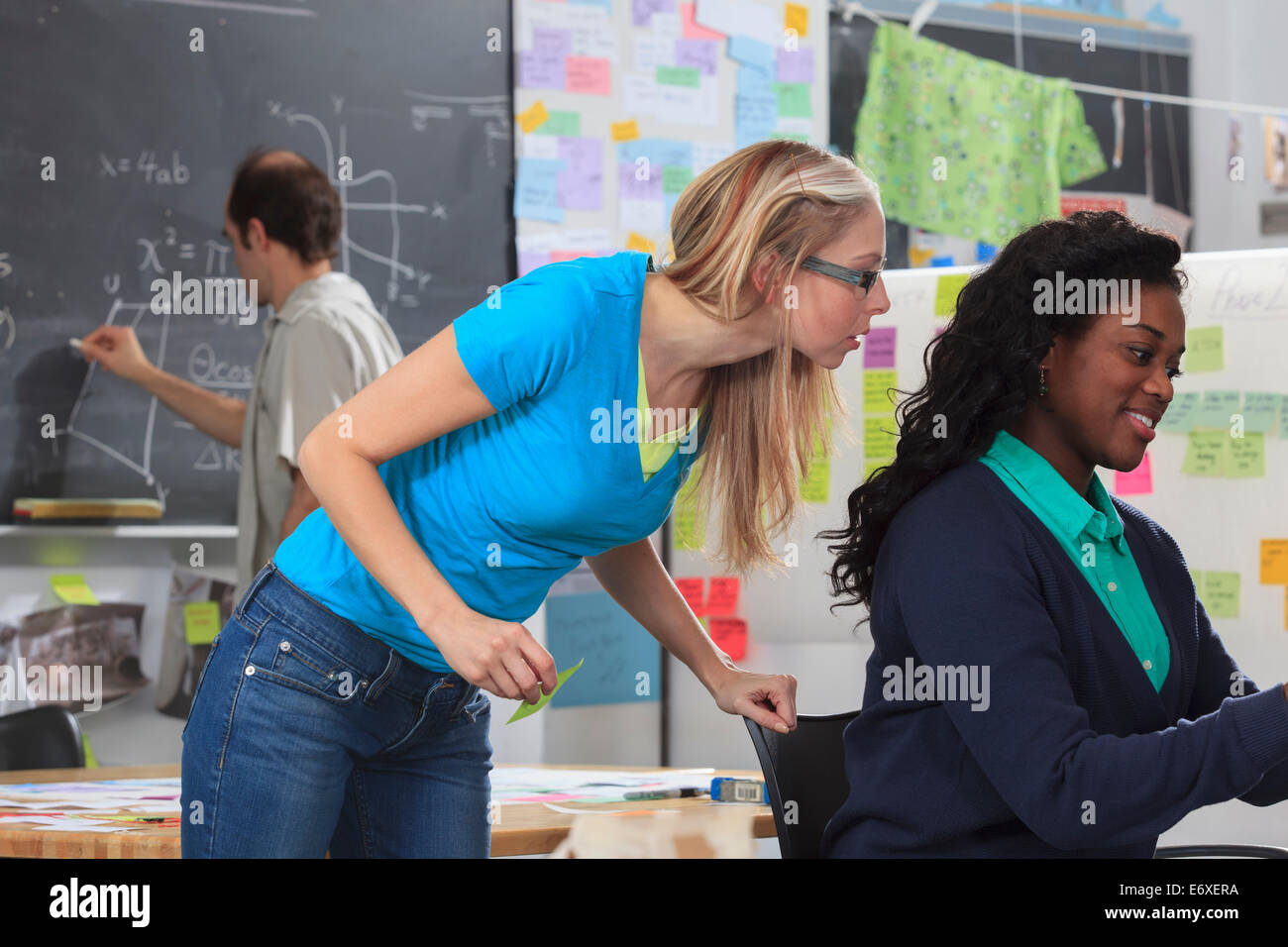 Engineering instructor writing math equations on blackboard while ...