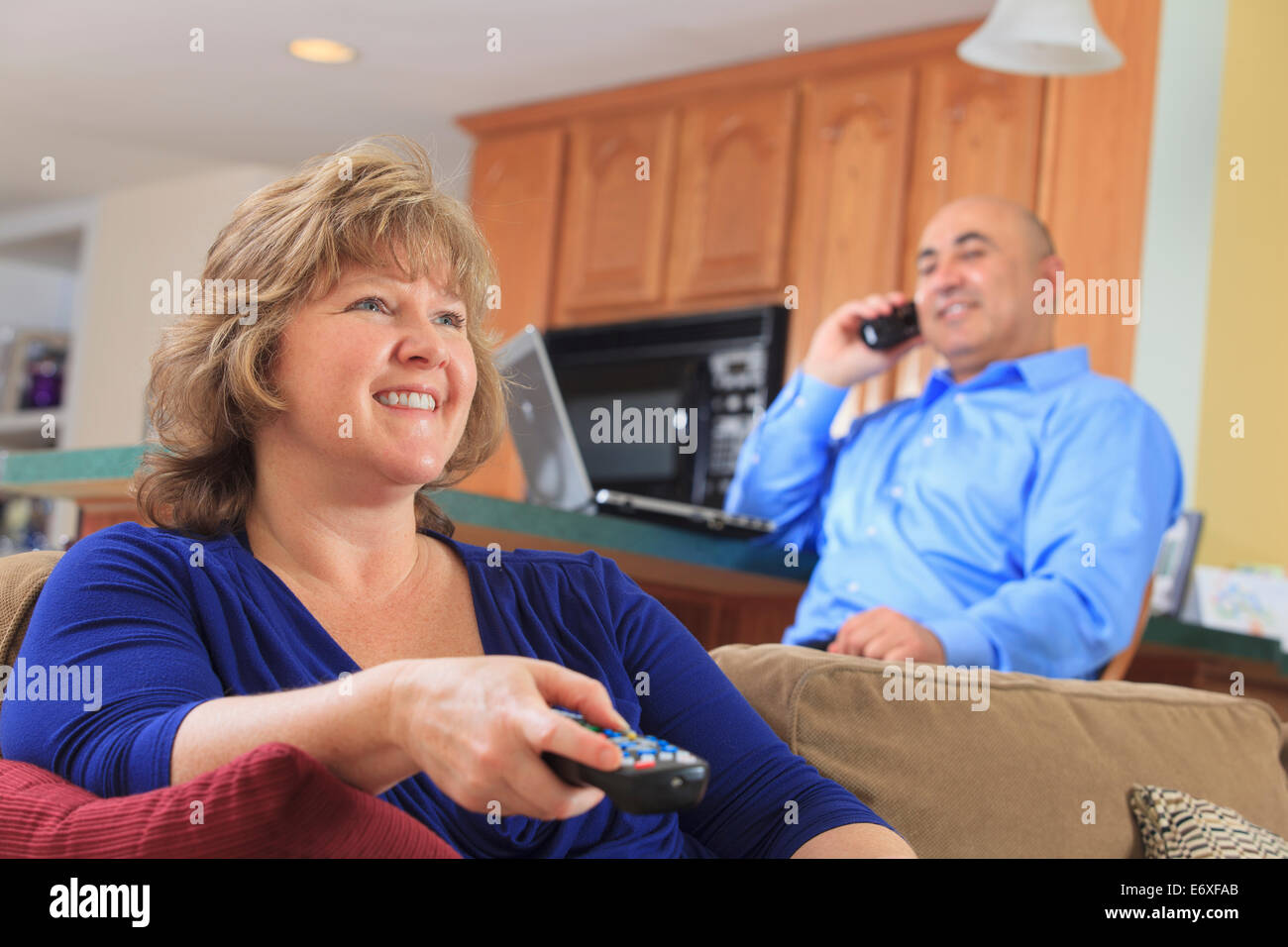 Wife using TV remote and husband using phone Stock Photo - Alamy