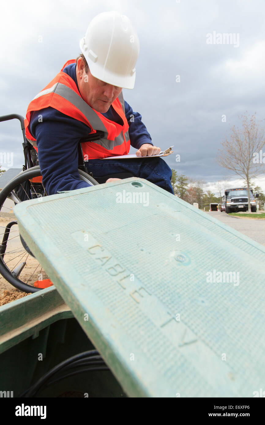 Construction engineer with spinal cord injury inspecting utility box ...