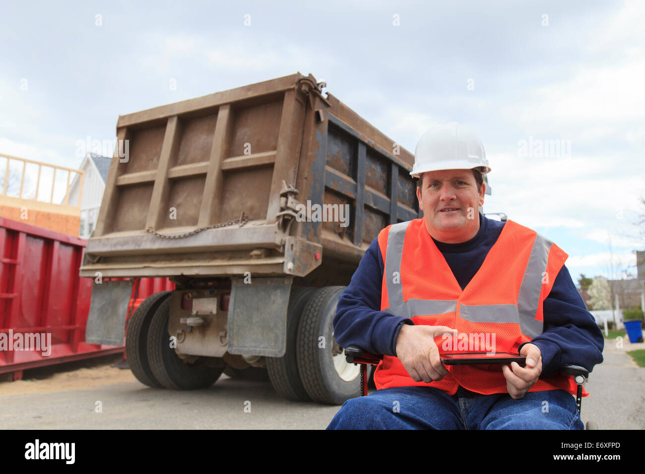 Construction engineer with spinal cord injury holding tablet on site ...