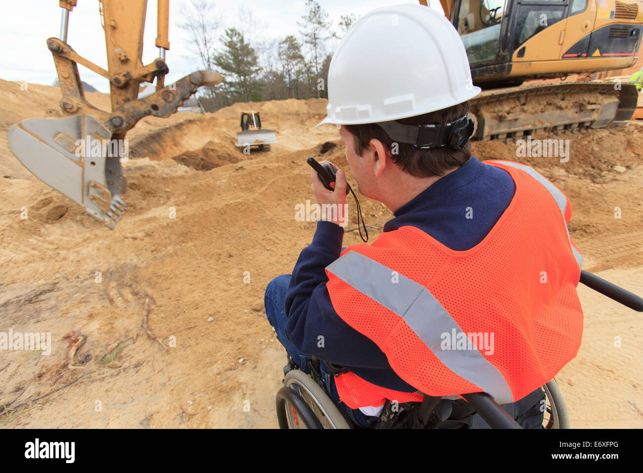 Construction engineer with spinal cord injury talking on portable radio ...