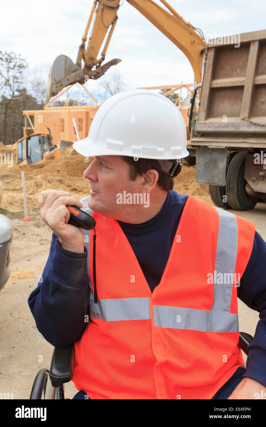 Construction engineer with spinal cord injury talking on portable radio ...