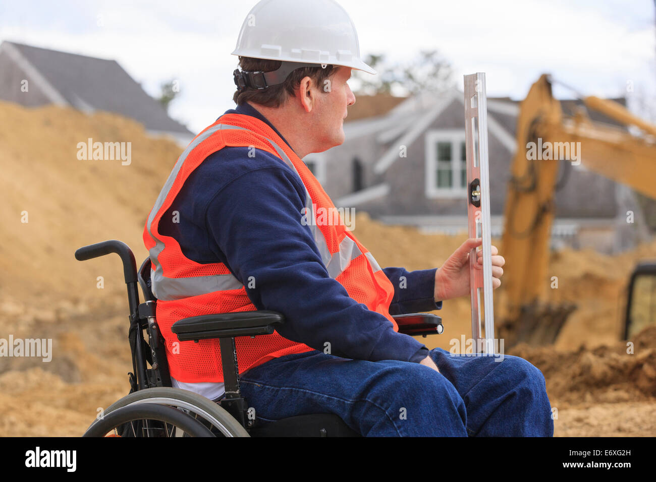 Construction engineer with spinal cord injury holding level at site ...