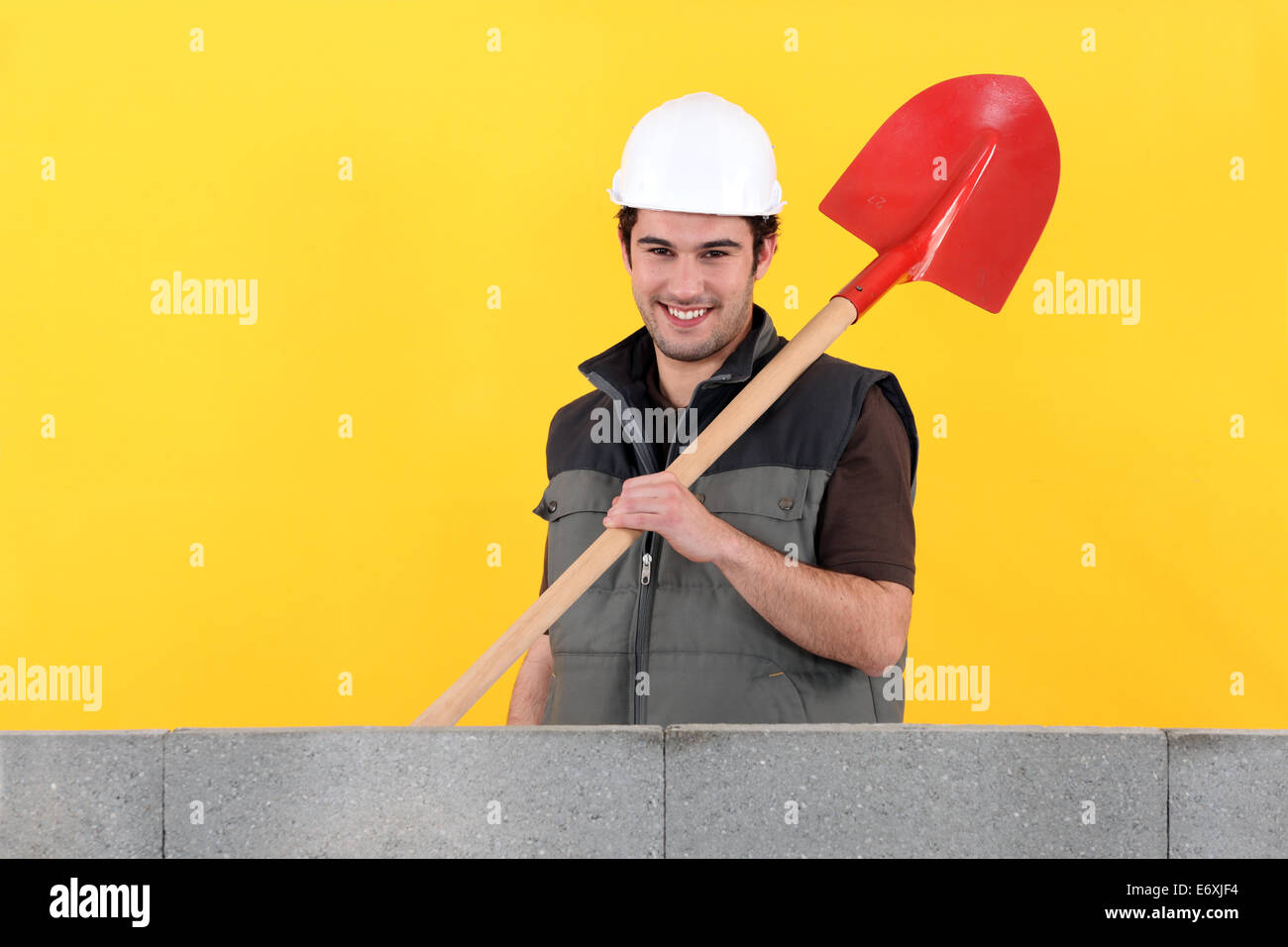 Happy mason stood by wall Stock Photo - Alamy