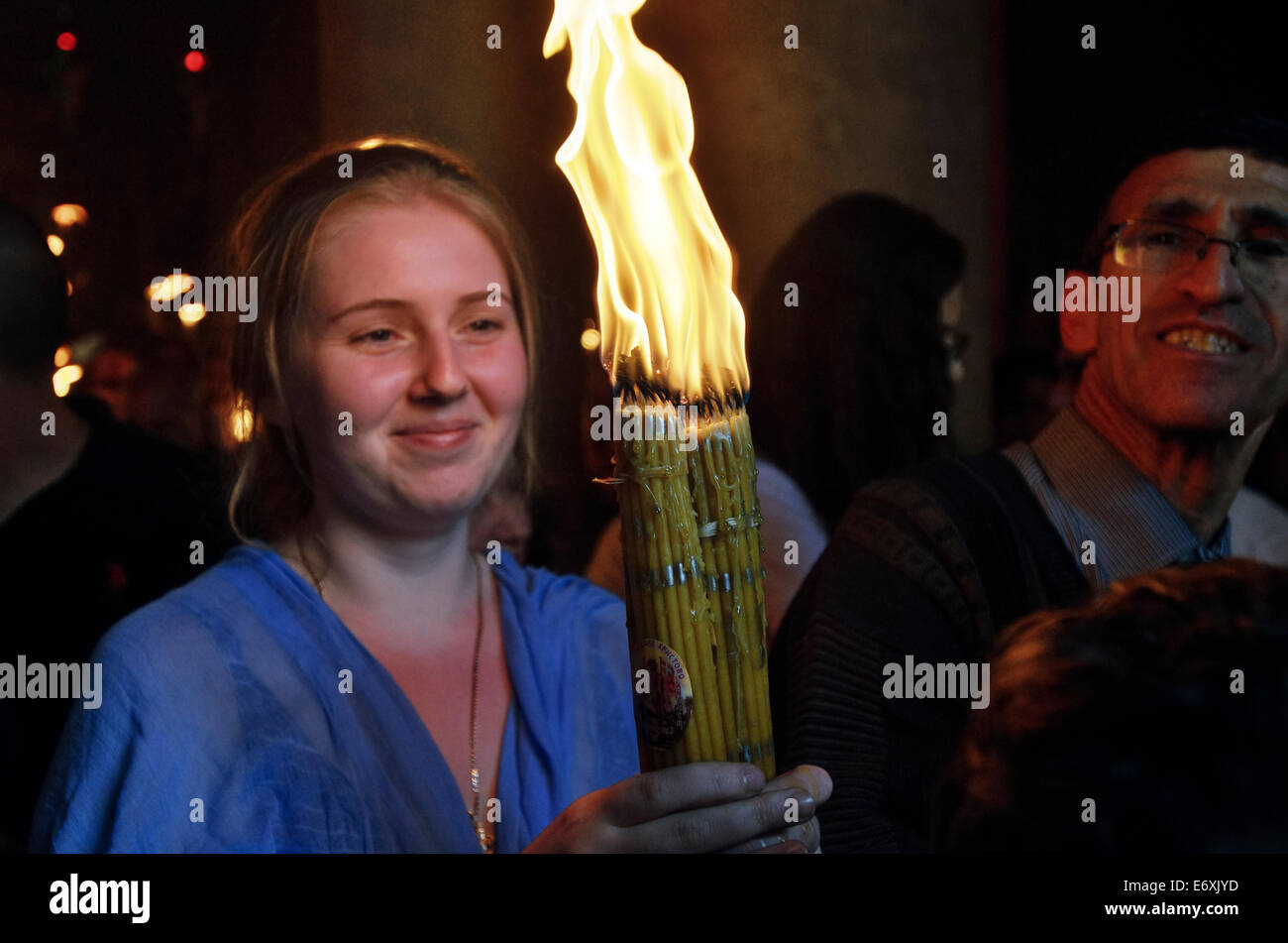 Young woman holds candles with fire in Church of the Holy Sepulchre ...
