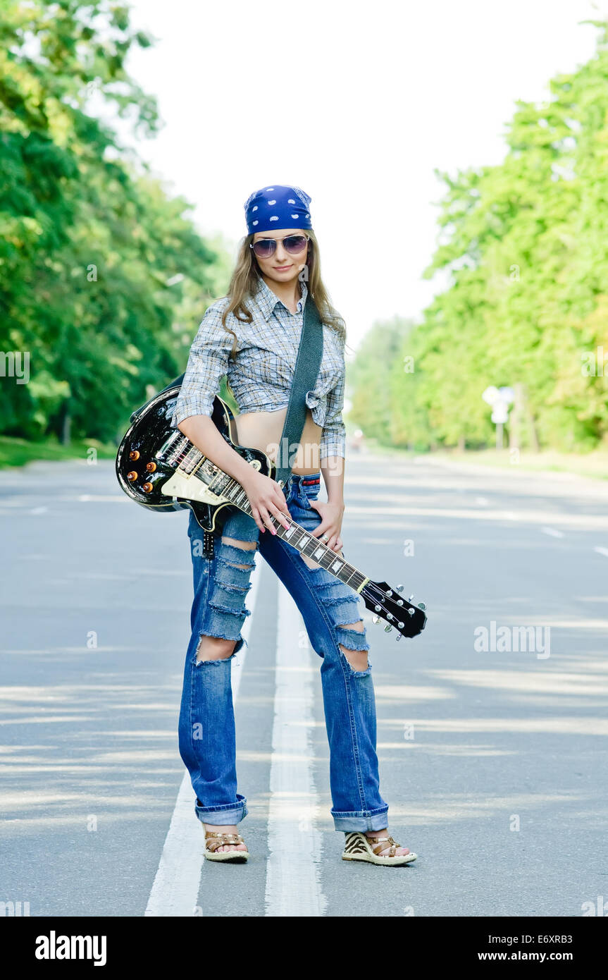 Rocking girl on a highway road with guitar Stock Photo - Alamy