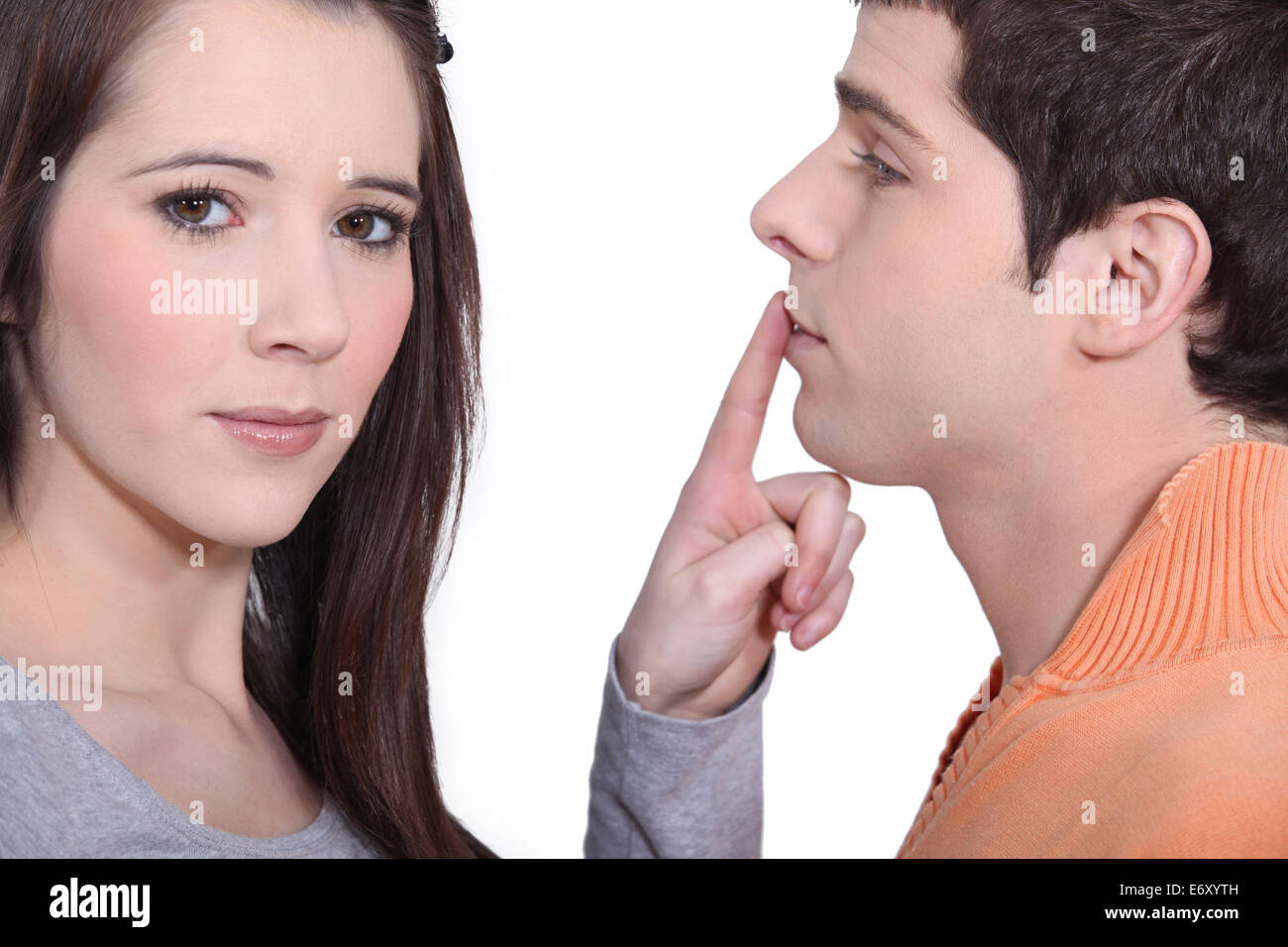 Girlfriend shushing boyfriend Stock Photo - Alamy